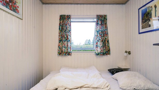 Quarto com cama, janela com cortinas, mesa de cabeceira e abajur.