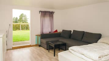 Quarto com sofá, cama, mesa pequena e janela com cortinas.