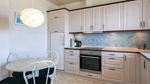 Uma cafeteira/bule, um frigorífico, uma placa de cozinha 