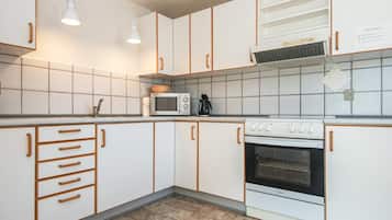 Cozinha com armários brancos, micro-ondas, forno e pia.