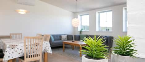 Uma área de refeições com mesa, cadeiras, um sofá e dois vasos de plantas.