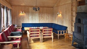 Um interior de madeira com um sofá, cadeiras, uma mesa e uma lareira.