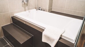 Um banheiro moderno com banheira, chuveiro e toucador preto.