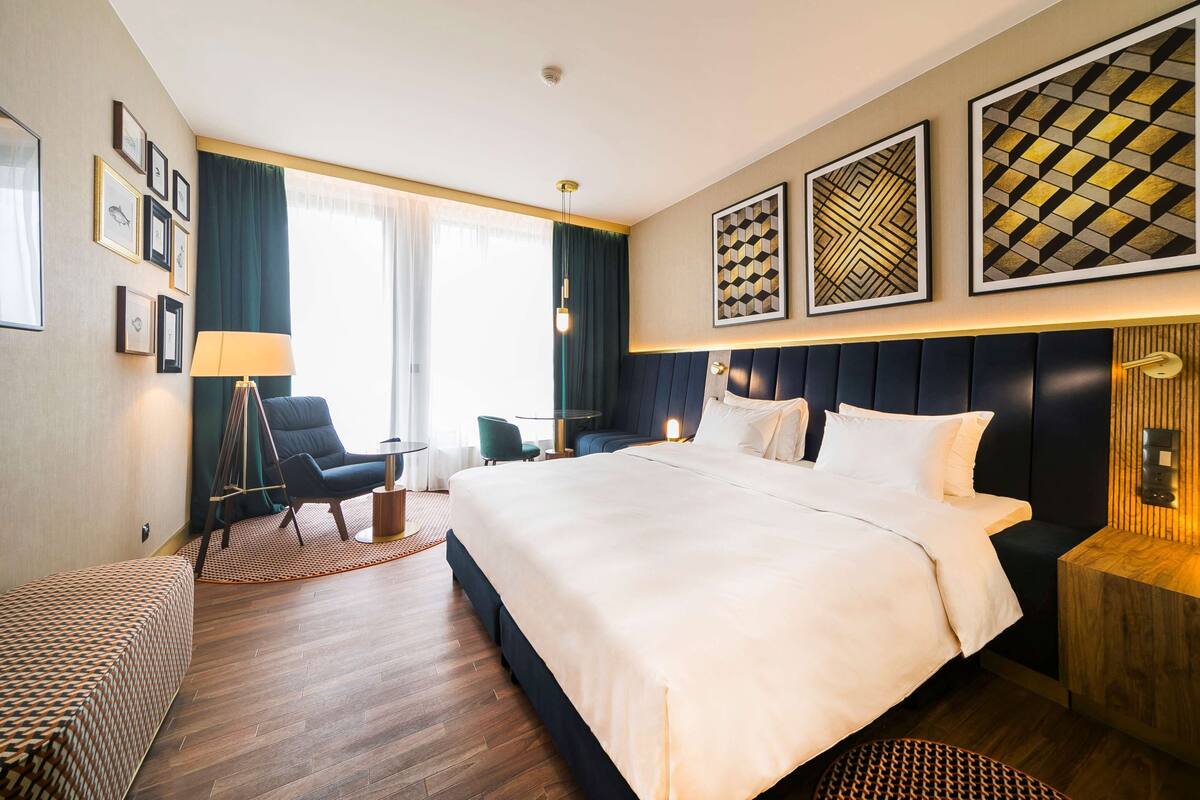 Quarto de hotel com uma cama grande, uma mesa, uma cadeira e um sofá.