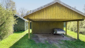 Um edifício térreo com telhado inclinado e varanda coberta.