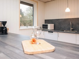 Cozinha moderna com micro-ondas, pia e bancada de madeira.
