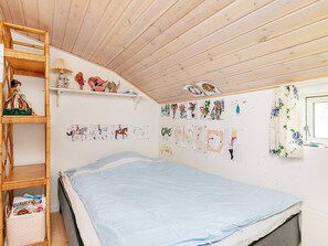 Quarto com cama, prateleira com bonecas e desenhos infantis na parede.