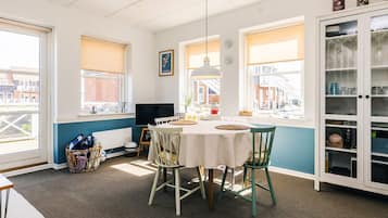 Uma sala de jantar com mesa, cadeiras e um armário com copos.