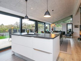 Cozinha moderna com ilha grande, iluminação pendente e amplas janelas com vista para o exterior.