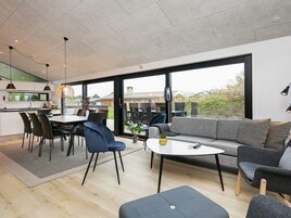 Um interior moderno com área de refeições, sofá e vista para o exterior.