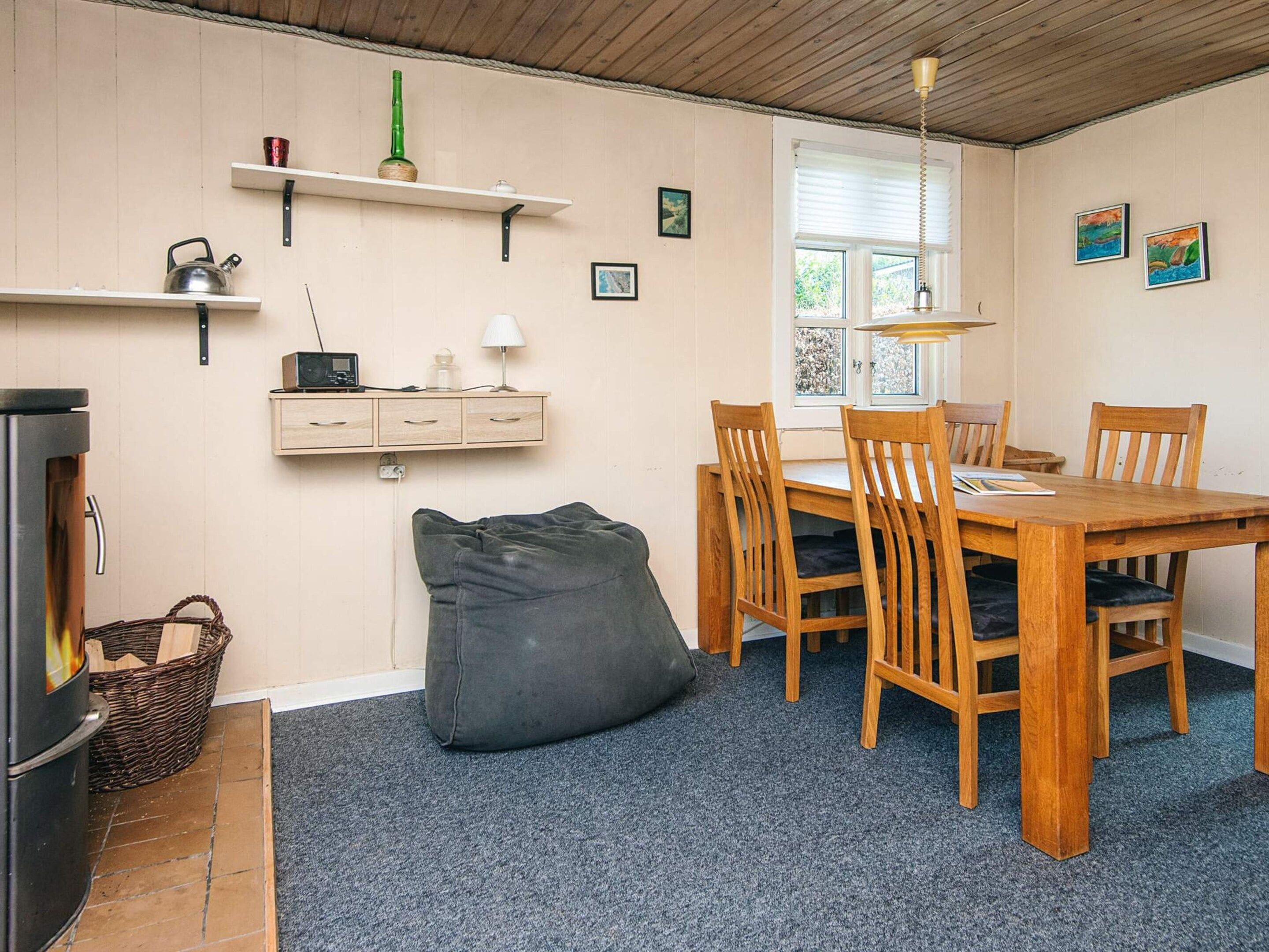 Um quarto acolhedor com uma mesa de jantar, cadeiras, um sofá, lareira e janela com persianas.