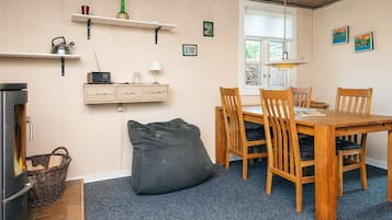 Um quarto acolhedor com uma mesa de jantar, cadeiras, um sofá, lareira e janela com persianas.