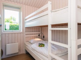 Quarto com beliche, janela, radiador e luminária.