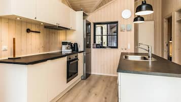 Cozinha moderna com painéis de madeira, forno embutido, cafeteira e janela com vista.