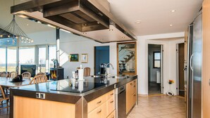 Uma cozinha moderna com uma ilha central, eletrodomésticos de aço inoxidável e uma grande janela com vista panorâmica.