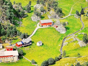 Vista aérea de uma propriedade rural com um celeiro, uma casa pequena e uma área cercada.