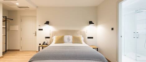Quarto moderno com uma cama grande, luminárias de cabeceira e porta de vidro para o chuveiro.