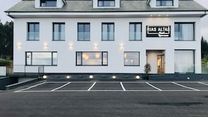 Um hotel moderno com fachada branca, várias janelas e uma placa com a inscrição 'RIAS ALTAS Hotel & Resorts'.