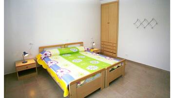 Quarto com cama, mesas de cabeceira, guarda-roupa e luminária na parede.