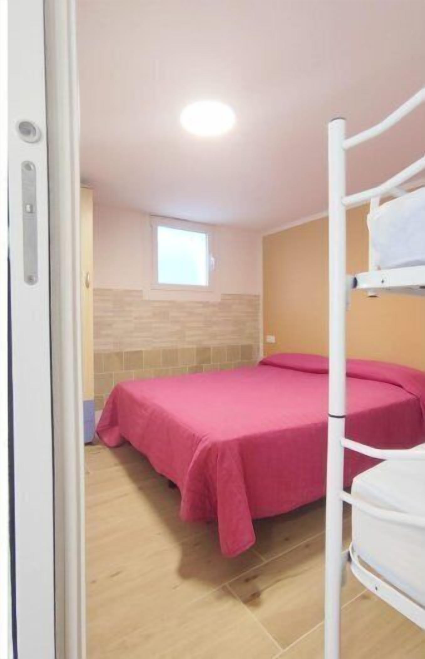 Quarto com beliche, janela e parede revestida com azulejos.
