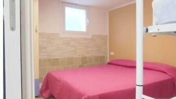 Quarto com beliche, janela e parede revestida com azulejos.