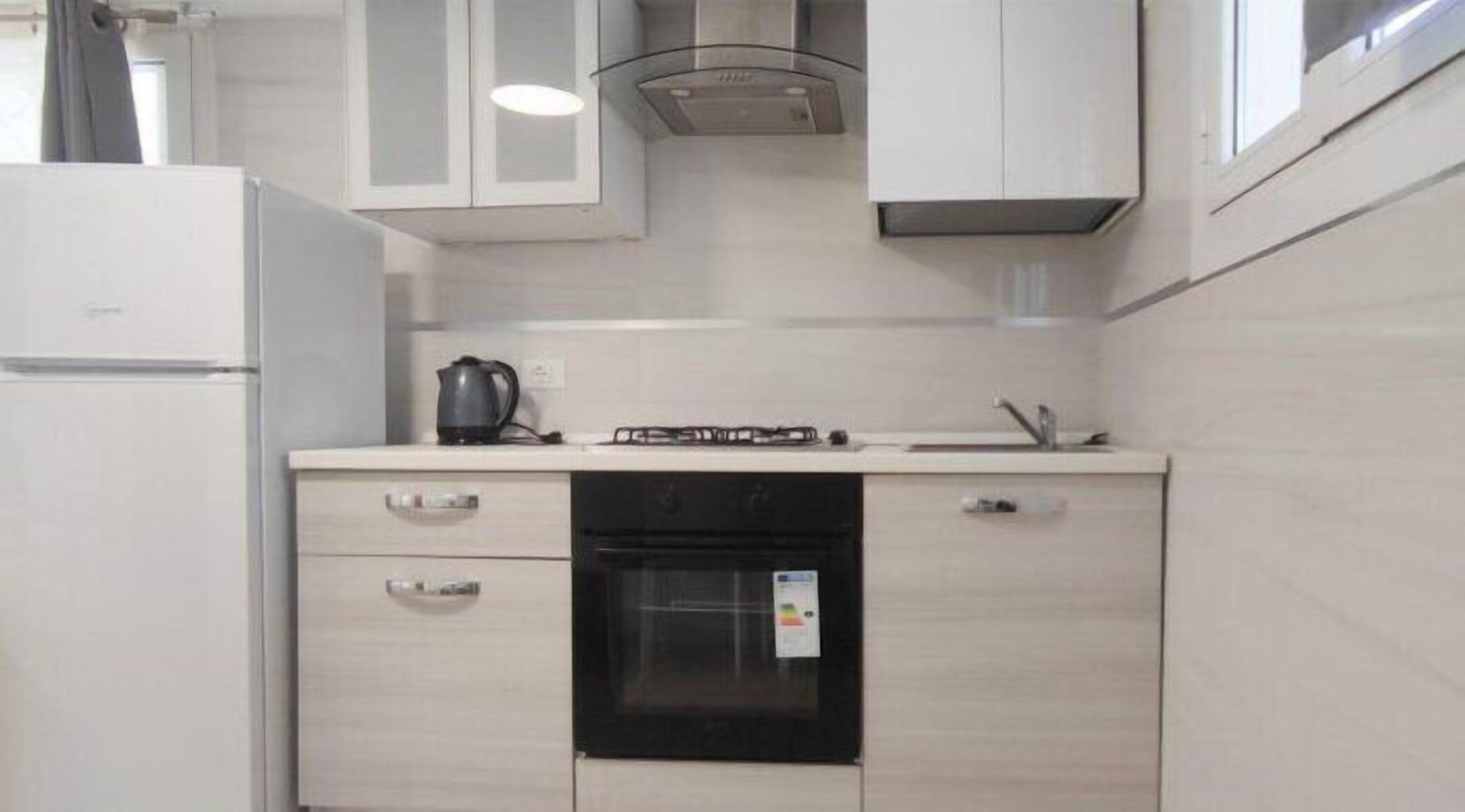 Uma cozinha moderna com máquina de lavar louça, forno e chaleira sobre o balcão.