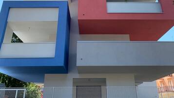 Um edifício com vários andares e varandas geométricas em azul, laranja e vermelho.