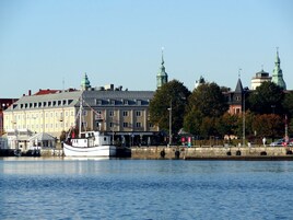 Vista para o cais com um edifício histórico, um barco atracado e um céu limpo.