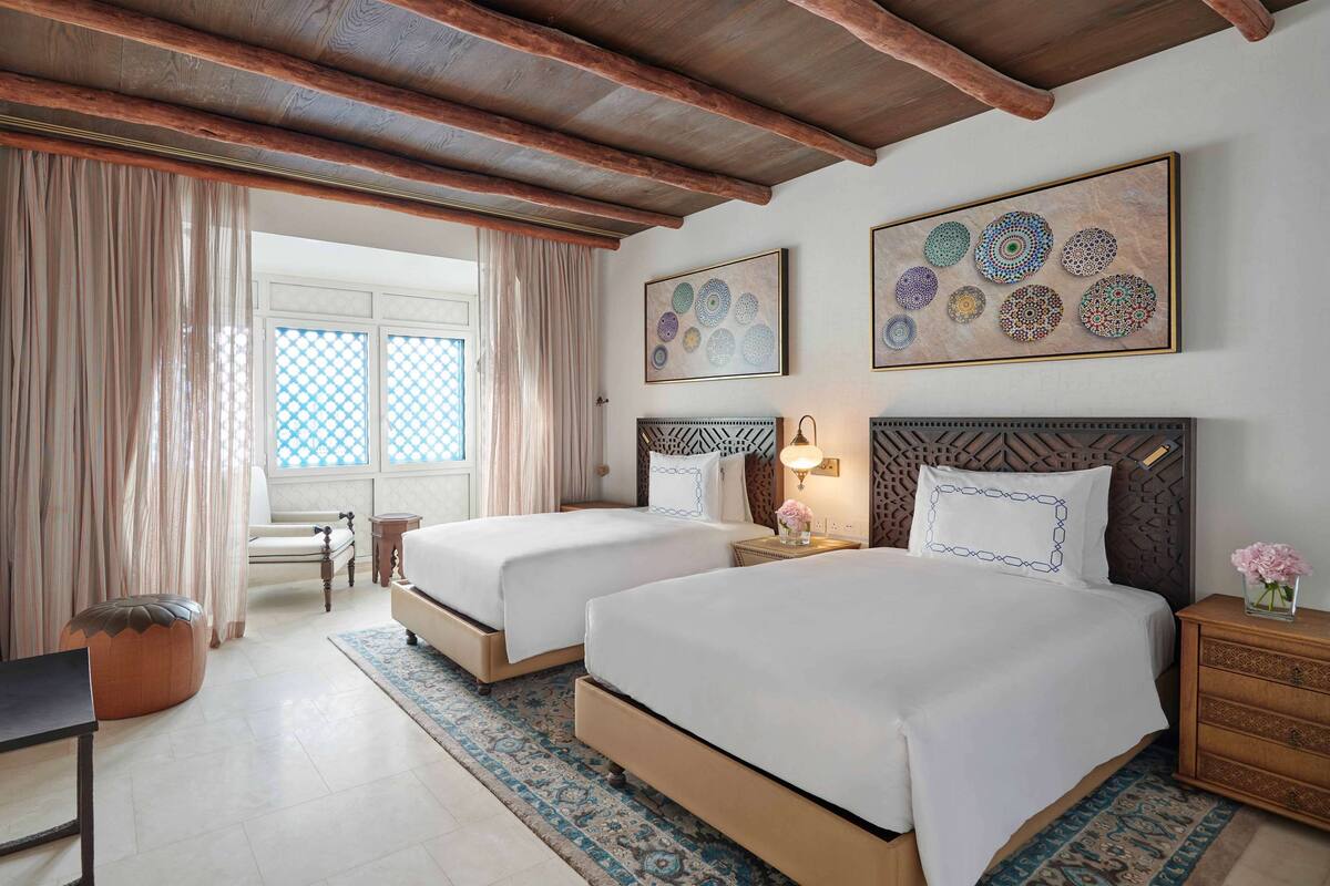Quarto de hotel com duas camas, teto de madeira, obra de arte estampada e vista pela janela com cortinas.