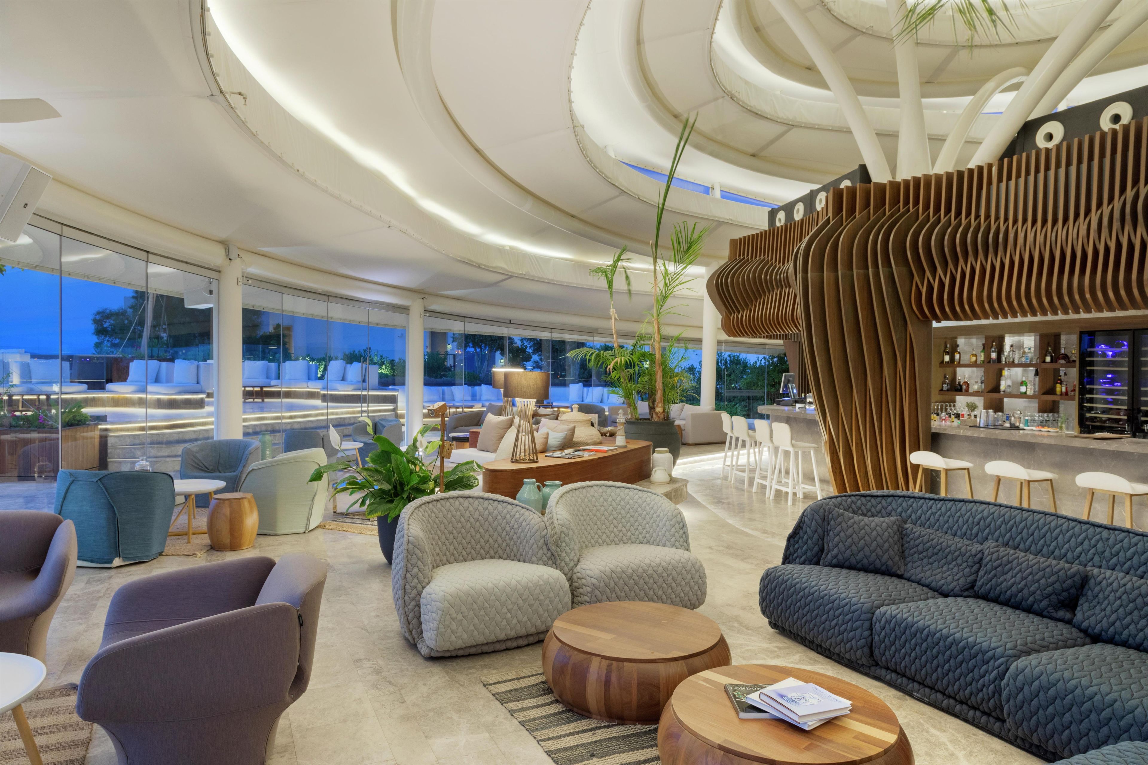 Uma área de lounge moderna com assentos, bar e amplas janelas.