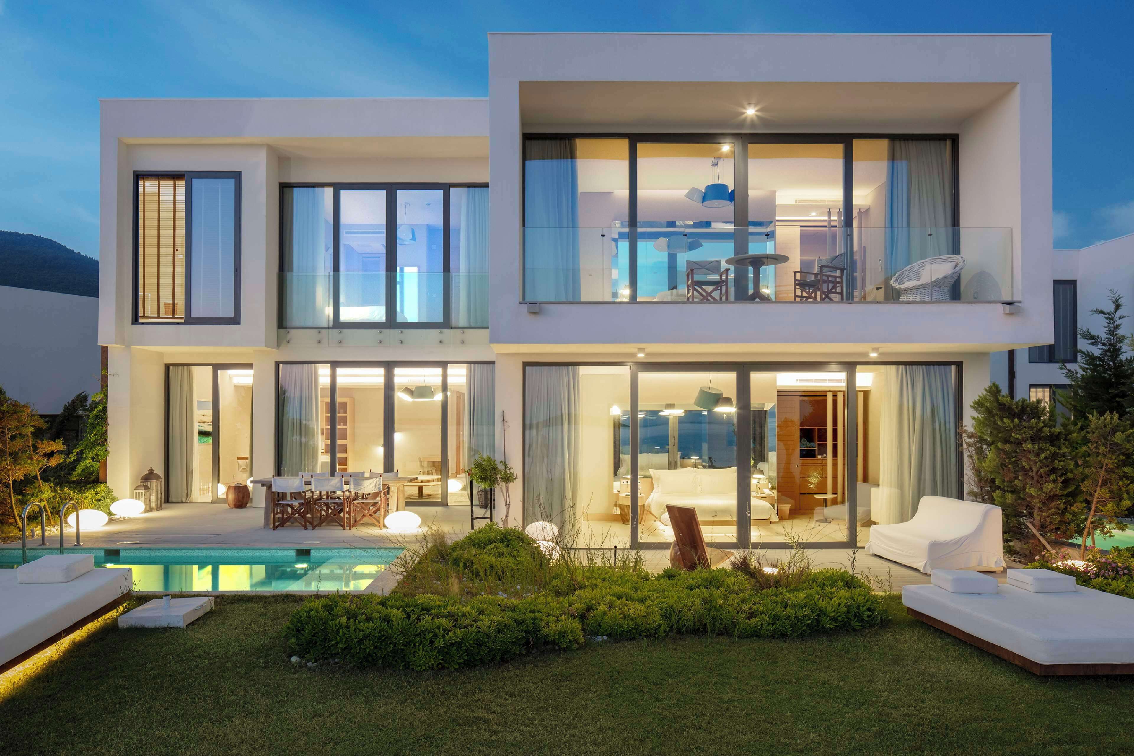 Uma casa moderna de dois andares com piscina, área de estar externa e varanda coberta.
