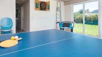 Quarto com mesa de pingue-pongue, dardos e futebol de mesa.