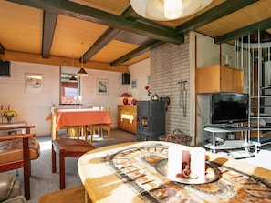 Uma sala de estar aconchegante com lareira, espaço de jantar e televisão.