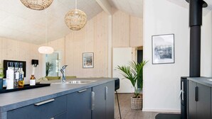 Uma cozinha moderna com ilha central, eletrodomésticos de aço inoxidável e fogão preto.