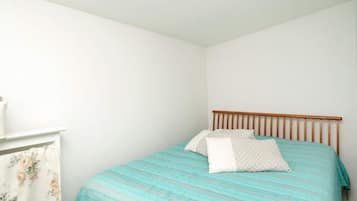 Quarto com cama, cabeceira de madeira e parede branca.