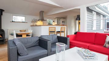 Uma sala de estar aconchegante com lareira, um sofá vermelho e uma mesa de centro branca.