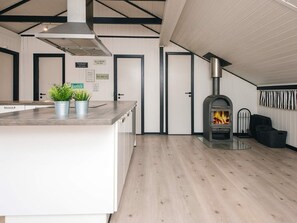 Cozinha moderna com ilha central, fogão a lenha e área de jantar com cortina listrada.