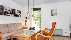 Uma sala de estar com sofá, mesa de jantar com cadeiras, luminária e obras de arte nas paredes.