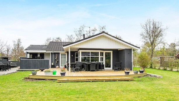 Uma casa moderna com um pátio, móveis de exterior e um gramado bem cuidado.