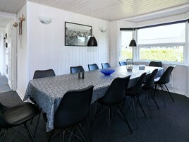 Uma sala de jantar com mesa posta para seis pessoas, rodeada por cadeiras pretas, uma tigela azul e um pendente preto.