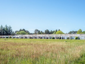 Uma fileira de edifícios térreos com telhado plano, possivelmente um motel ou camping, situada em um campo gramado com árvores ao fundo.