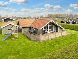 Um bairro residencial com várias casas, um deck de madeira com mobiliário externo e um escorrega azul.