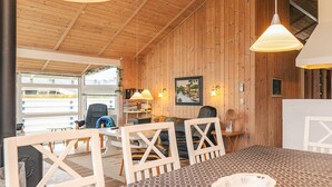 Quarto acolhedor com paredes de madeira, uma mesa de jantar, cadeiras e vista para o exterior.