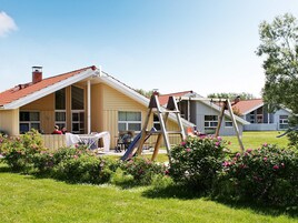 Uma fileira de casas com telhados inclinados, gramado e parquinho.