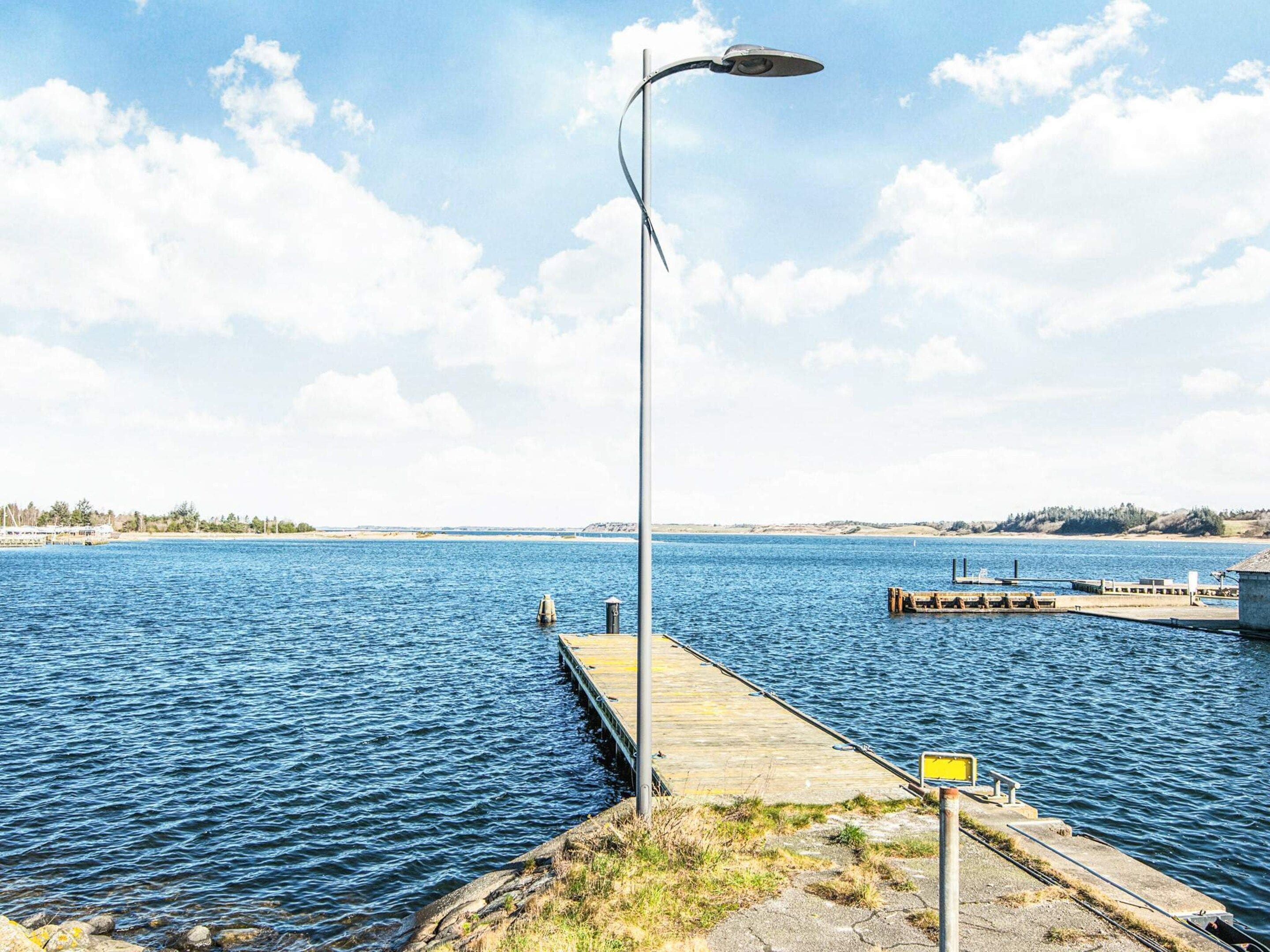 Um cais que se estende sobre a água, com um poste de luz e uma placa.