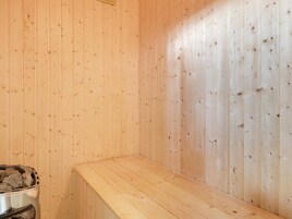 Uma sala de sauna com paredes e banco de madeira.