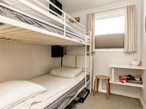 Quarto com beliche, janela, um banquinho pequeno e prateleira com objetos.
