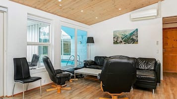 Uma sala de estar moderna com vista para a piscina, móveis de couro e piso de madeira.