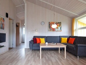Uma sala de estar moderna com um sofá cinzento, mesa de centro de madeira e um quadro na parede.