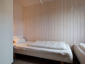 Uma cama de solteiro em quarto com paredes de madeira.